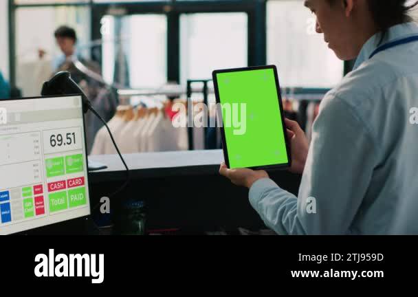 Asian store worker looking at chroma key green screen mock up tablet ...