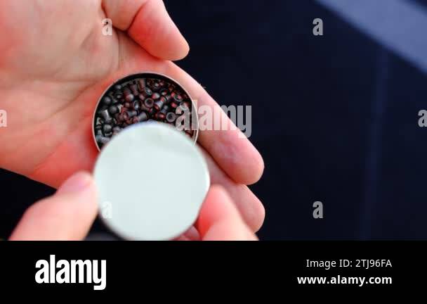 air gun pellets on the mans hand with red light for illumination. Man ...