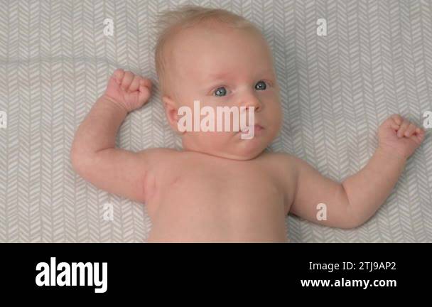 Sad newborn baby is crying in bed. Upset baby boy shouting and ...