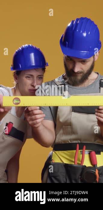 Vertical video: Construction workers using water level tools to measure ...
