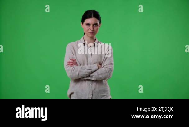 Aggressive and furious woman is standing on a green screen background ...