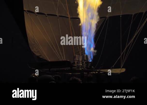 Close-up of balloon at night as it inflates for flight, burning burner ...