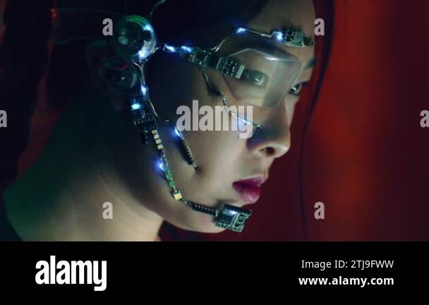Focused asian girl in cyberpunk attire works on the computer. Wearing ...