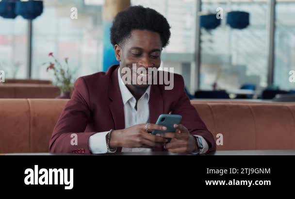 A man dressed in a suit typing on his phone, clicking his fingers on a ...
