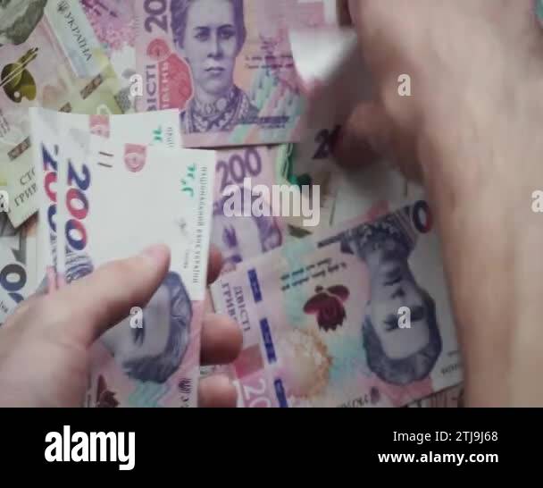 A man collects Ukrainian paper money of different denominations in one ...