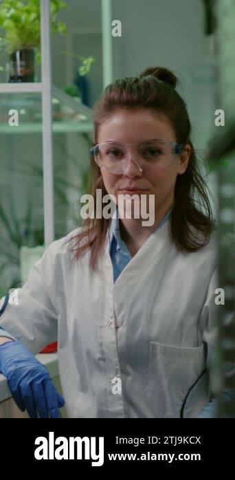Vertical video: Portrait of chemist woman in white coat working in ...