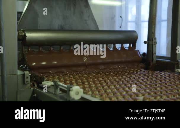 static medium shot of pouring candies with chocolate in a chocolate ...