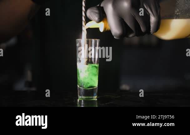 Cocktail Shots. close-up. bartender is pouring different alcoholic drinks in layers, into shot ...