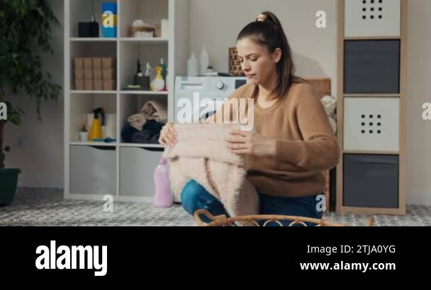 Lonely girl sitting on floor in the bathroom and taking clothes out of ...