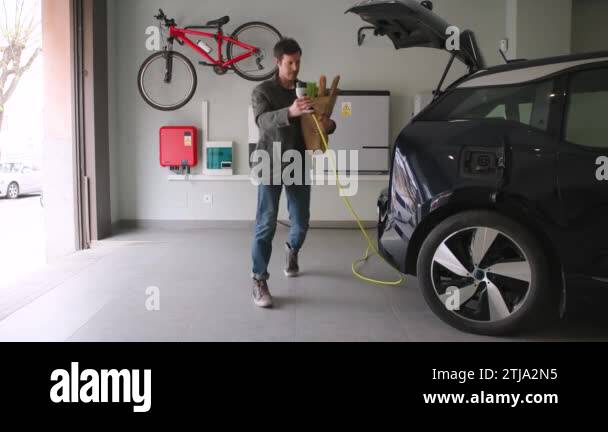 Man multitasking arrives home after shopping at the grocery store and ...