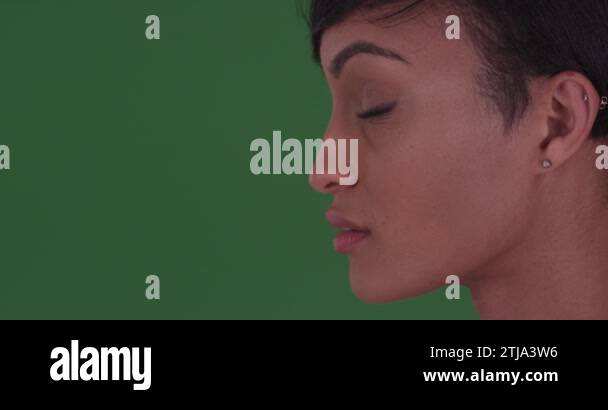 Side view of Beautiful woman turning to face camera on green screen. On ...