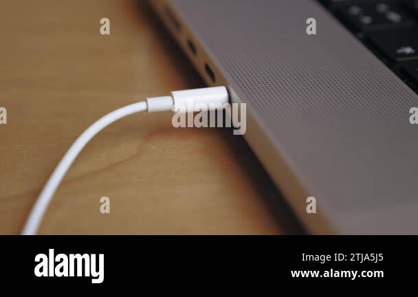 A person pulls out headphones into the headphone jack of a laptop ...