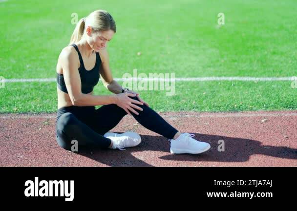 runner athlete with muscle pain sitting on the track of stadium Woman ...
