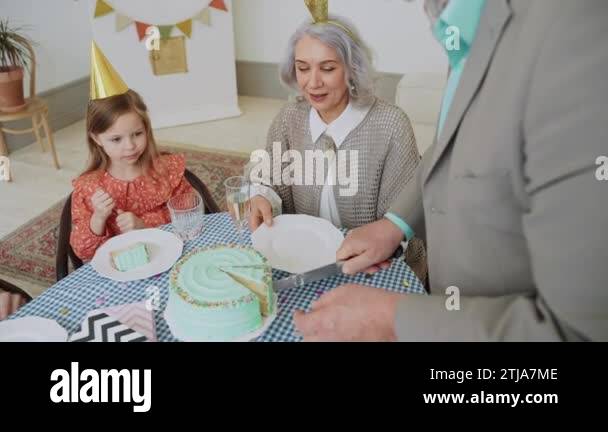 An elderly man cuts a cake at the girls birthday dinner for whole ...