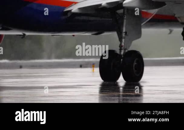 Chassis close-up, wet runway. Airliner taxiing in a downpour. Aircraft ...