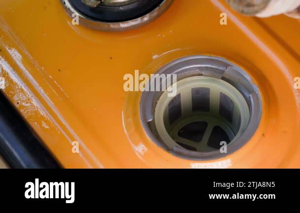 Fuel is poured into the fuel tank of a yellow gas generator from a ...