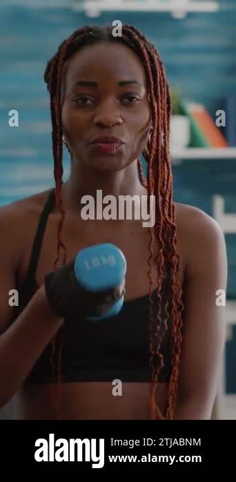 Verical video: Slim black trainer exercising body muscles recording ...