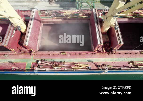 Loading dry cargo ship of wheat by cranes in port. Aerial view loading into holds of sea cargo ...