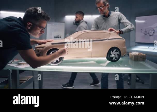 Two male automotive designers creating futuristic plasticine clay model ...