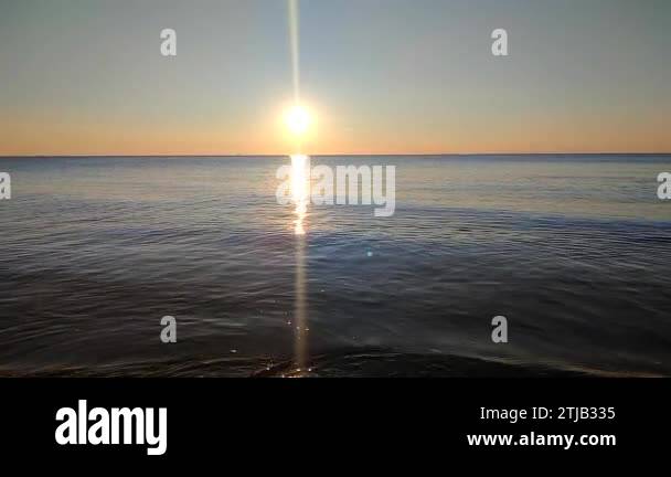 Dawn sunset on sea. Sun above horizon. Calm blue water surface, small ...