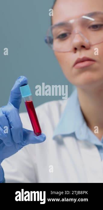 Vertical video: Microbiology doctor studying vacutainer with liquid ...