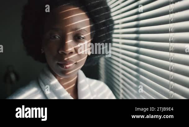 Face, window and light with a black woman standing in her home with the ...