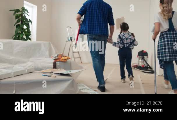 Dad, daughter and wife enter new home. They hold paint rollers and ...