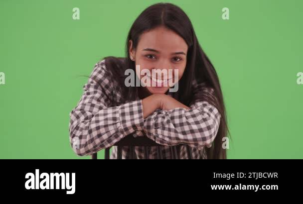 Smiling Hispanic Girl Sitting Backwards In Her Chair With Her Arms Crossed On Green Screen On
