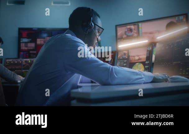 African American flight control employee in headset monitors space ...