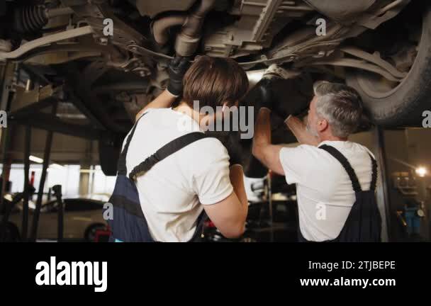 Two mechanics in uniform father and son are working in auto service ...