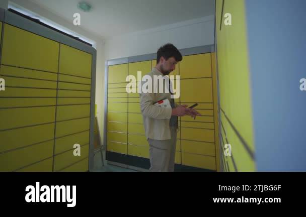 Man uses yellow packing station to send package by self-service. German ...