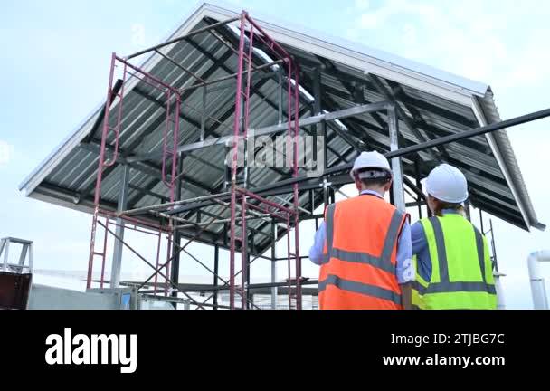 Young engineers working. Plan for construction of a warehouse. See the ...