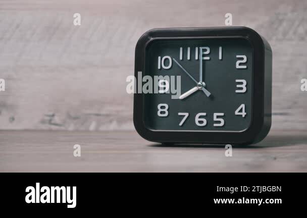 An arrow clock of square shape on wooden table shows time 8 oclock ...