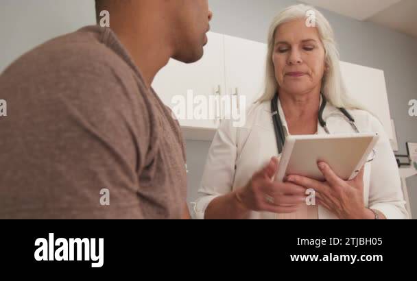 Closeup of mature female doctor using tablet computer to take notes of ...