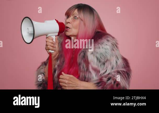 Smiling happy stylish old woman talking with megaphone, proclaiming ...