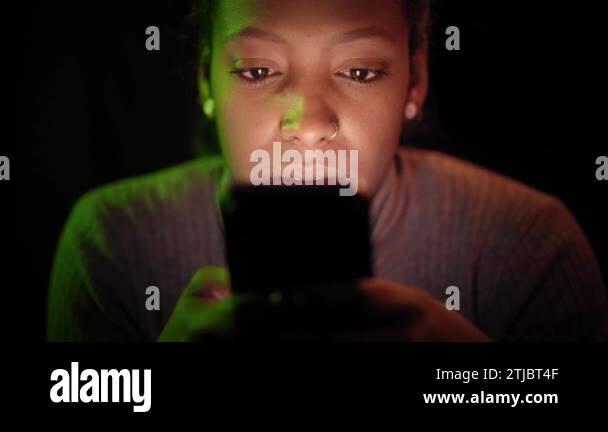 Serious woman using a mobile phone in the dark. The screen of the ...