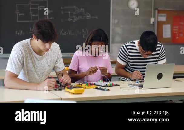 Diverse high school students group working on electronic project in science robotics lesson ...