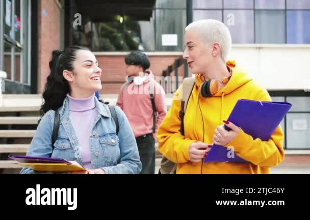a group of two young female students walking and talking about gossip ...