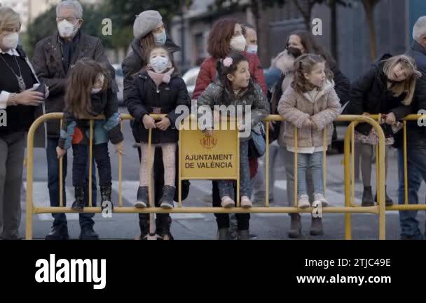 Young Girls Standing On A Steel Barricade Fence With Their Parents On ...