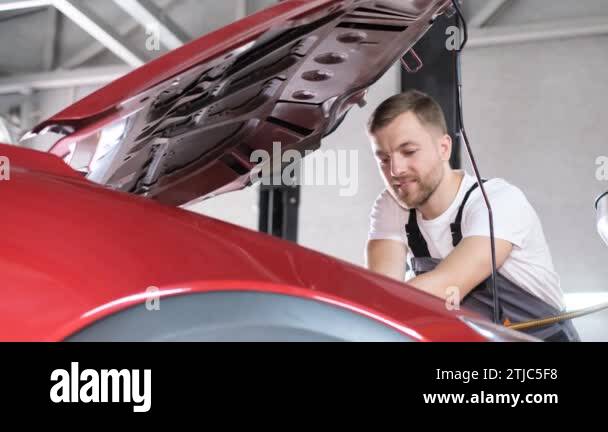 Attractive happy car mechanic with american look working in car repair ...