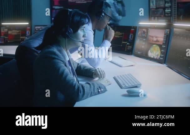 Female flight control operator with African American coworker monitor space mission on computer ...