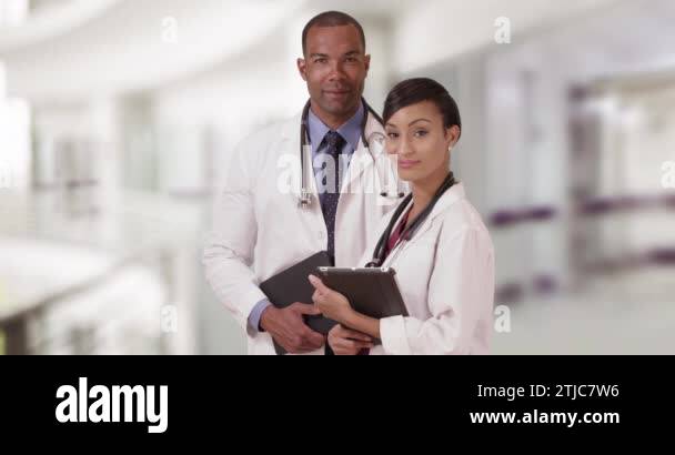 Two African American doctors posing for a portrait while holding their ...