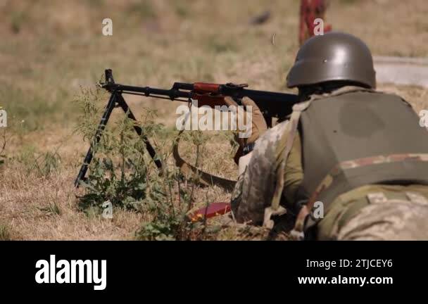 Armed military man unloading machine gun while lying with gun, soldier ...