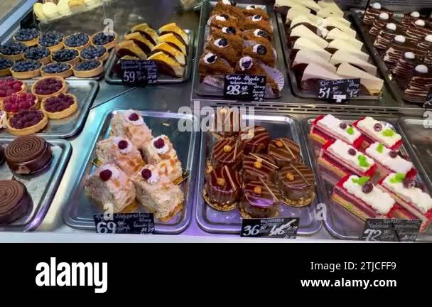 Showcase of confectionery with cakes and macarons in display for sale ...