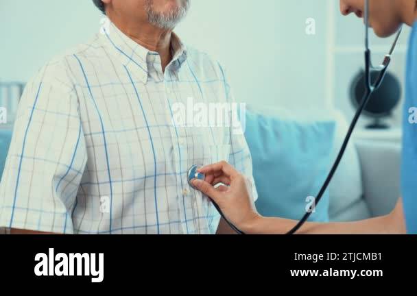Caring young female doctor examining her contented senior patient with ...