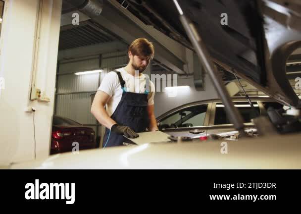 Team of two positive friendly car mechanics using a computer laptop to ...