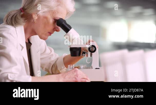 Scientist in white lab coat examining substance using microscope ...