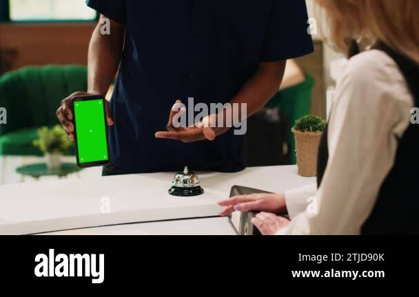Hotel guest showing greenscreen on phone, pointing at isolated display ...