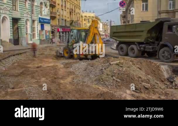 Industrial yellow excavator moving soil and loading into a dumper truck ...