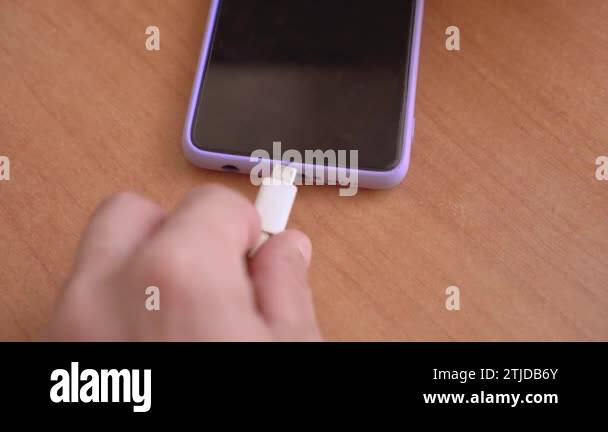 Old cable inserted into smartphone, charger broken, close-up of broken ...